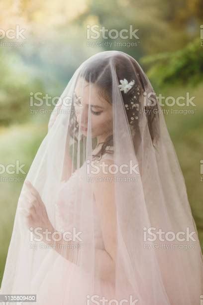 데이지와 흰 꽃으로 장식 된 곱슬 머리를 가진 매력적이 고 달콤한 젊은 여자는 신비 하 게 베일 아래 그녀의 얼굴을 숨 깁니다