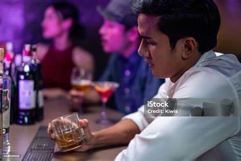 아시아 우울증 남자는 마음이 상하고 술집에서 맥주를 마시는 느낌 카운터 바에 앉아 외로움을 느끼는 술 한 병을 들고 나이트 클럽에서 혼자 술에 취해 숙취를 느끼는 매력적인