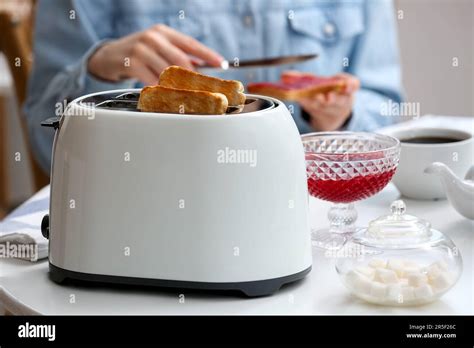 Woman Making Delicious Jam Toast At Table With Modern Toaster Stock Photo Alamy