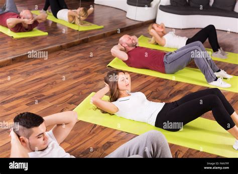 Young Fitness Coach Showing To Adult Learners New Exercise At Class
