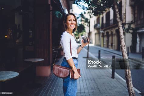 트렌디 한 웨어에 쾌활한 백인 여성의 반 길이 초상화는 마을에서 목적지를 즐기는 컵을 갈 커피를 들고 테이크 아웃 컵산책 여성 여행자는 도시 설정을 탐험 30 34세에 대한