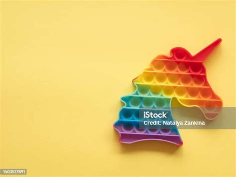 멀티 컬러 인기있는 유니콘 모양의 실리콘 안티 스트레스 팝 그것은 텍스트를위한 공간이있는 노란색 배경 평면도에 장난감 패션 현대 감각 키즈 장난감 Fidget 푸시 그것을