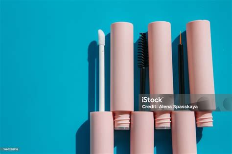 화장품과 브러쉬의 분홍색 튜브가 파란색 배경에 놓여 있습니다 공간을 복사합니다 립스틱의 닫힌 튜브 액체 립글로스 마스카라 아이 라이너 카잘 아이라이너에 대한 스톡 사진 및