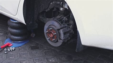 러그 너트와 렌치가 땅에 누워 있는 차고 작업장에서 타이어 교체 중에 브레이크 디스크와 브레이크 패드가 노출된 자동차 휠 허브 브레이크에 대한 스톡 사진 및 기타 이미지