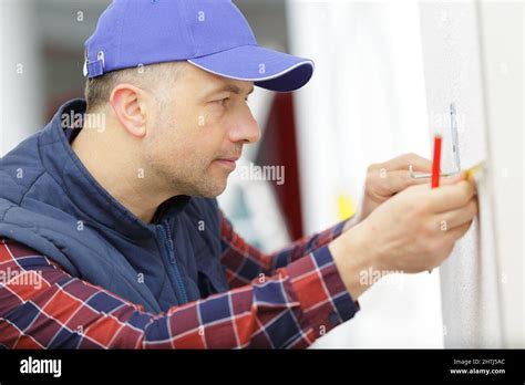 Male Electrician Installing Security System Door Sensor On Wall Stock