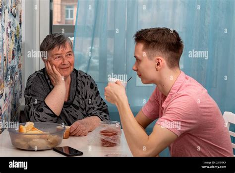 Happy Grandmother And Her Adult Grandson Drinking Tea And Discussing Latest News Selective