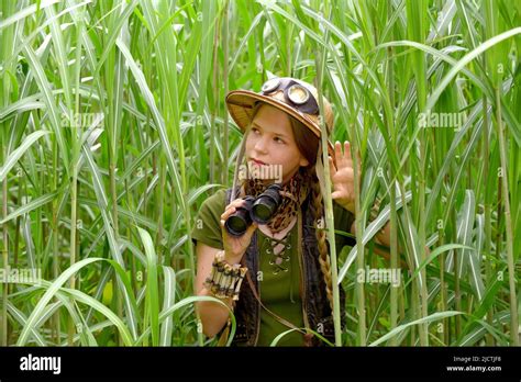 A Young Teenage Explorer Is Seen In Tall Grass She Holds A Pair Of