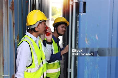 스마트 휴대 전화와 워키 토키 무선 제어 적재 컨테이너 상자를 사용하는 감독 안전모를 쓴 작업자가 컨테이너 화물 현장에서 일하고 산업용 컨테이너 화물 화물선을 점검하고 있다
