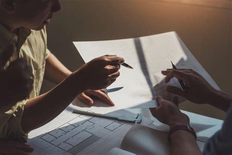 Premium Photo Midsection Of Architects Analyzing Blueprints On Table In Office