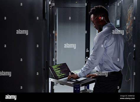 Side View Portrait Of Black Man As Network Engineer Using Laptop While