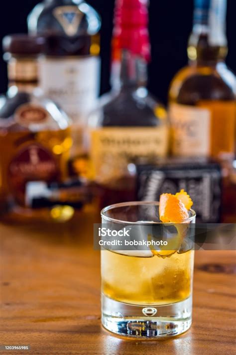 바 카운터에 얼음 큐브가 있는 위스키 한 잔과 배경에 병이 있습니다 0명에 대한 스톡 사진 및 기타 이미지 0명 갈색 금
