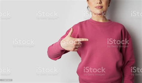 젊은 Hipster 소녀 핑크 Hoody와 포인팅 손가락 귀하의 로고 또는 디자인에 대 한 공간을 입고 분홍색 배경에 흰 빈