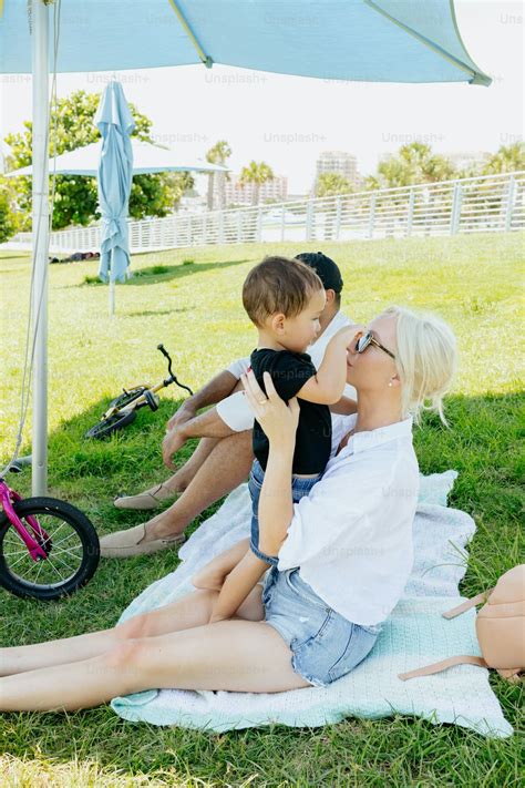 한 여자와 두 아이가 우산 아래 담요 위에 앉아 있다 사진 Unsplash의 바깥 이미지