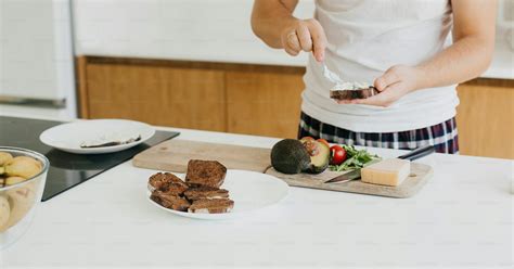 현대적인 흰색 주방에서 아보카도로 건강한 토스트를 만드는 사람 곡물 빵 아보카도 토마토 루꼴라 및 치즈로 만든 샌드위치 가정 요리 개념 사진 Unsplash의