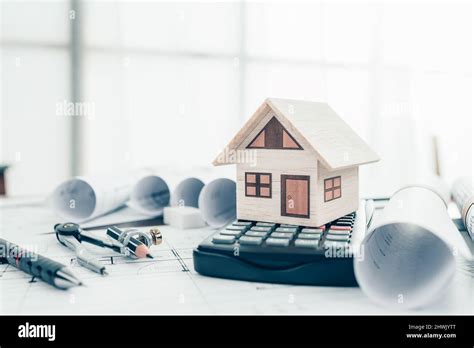 Mini Model House On Calculator Pencil Compass And Roll Blueprint Plan On Blueprint House Plan