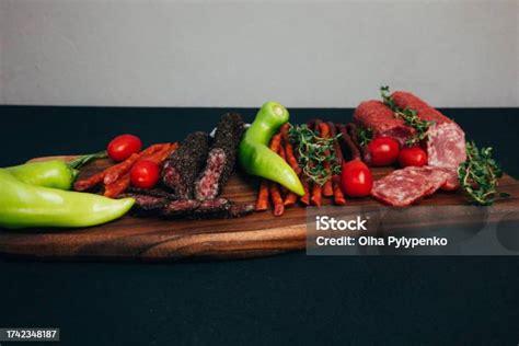 녹색 종이와 토마토가 든 나무 쟁반에 다양한 종류와 크기의 소시지 어두운 배경에 훈제 소시지 세트 가공육에 대한 스톡 사진 및 기타 이미지 Istock