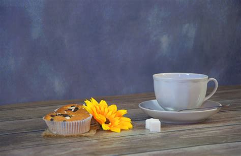 노란 꽃과 설탕 큐브 옆에 있는 섬유 냅킨에 신선한 머핀 두 개와 접시에 흰색 세라믹 컵에 홍차 를 조금 더 넣습니다 0명에 대한 스톡 사진 및 기타 이미지 Istock