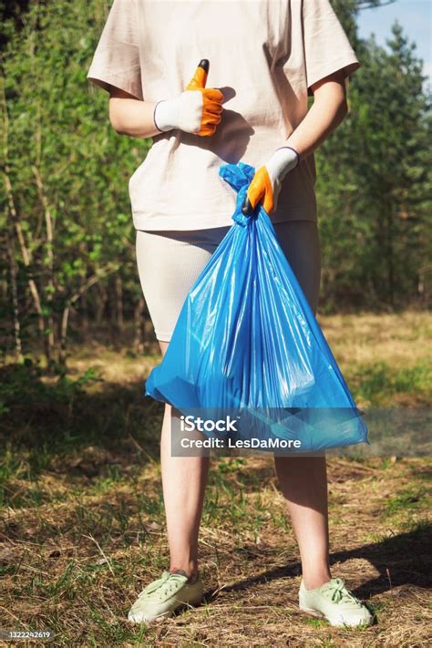 자원봉사자가 숲에서 플라스틱 병을 모으고 있다 소녀는 손에 쓰레기 봉투를 들고 그녀의 손으로 제스처를 보여줍니다 위대한 클래스 환경 지구를 보호하기 위한 개념 호출 30