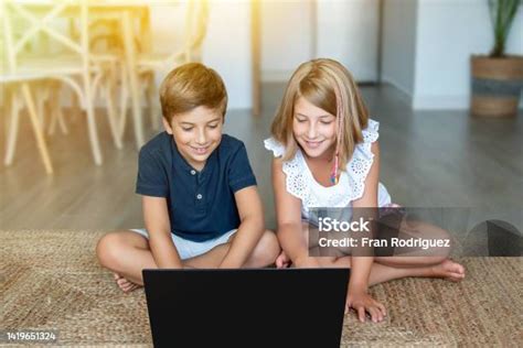 거실 바닥에 앉아 노트북 컴퓨터를 가지고 놀고 배우는 두 아이 학교와 신기술로 돌아가기 10 11세에 대한 스톡 사진 및 기타 이미지 10 11세 2명 6 7 살