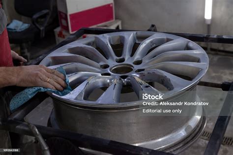 마스터 바디 수리 남자 워크숍에서 이후의 그림 청소 및 수평 연마 재료의 도움으로 휠 자동차의 알루미늄 바퀴의 표면 준비 작업은 바퀴에 대한 스톡 사진 및 기타 이미지
