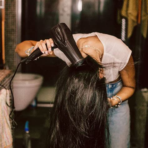 An Image Of A Woman Flipping Her Hair Upside Down While Drying It With