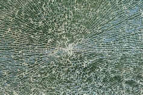 금이 간 유리 주거용 건물 외부에서 꺼내 푸른 배경에 깨진 유리의 질감 표면에 금이 갔습니다 깨진 총알 뒤의 구멍 깨진 유리가 있는 배경 강화 유리에 대한 스톡 사진 및