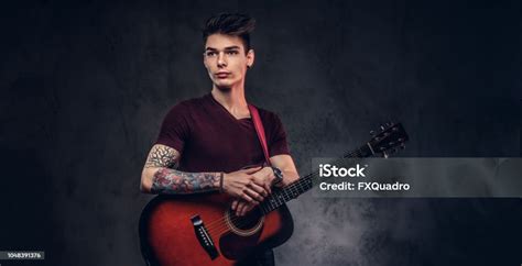 그의 손에 기타와 함께 T셔츠 포즈에 세련 된 머리와 잘생긴 젊은 음악가 T 셔츠에 대한 스톡 사진 및 기타 이미지 T 셔츠