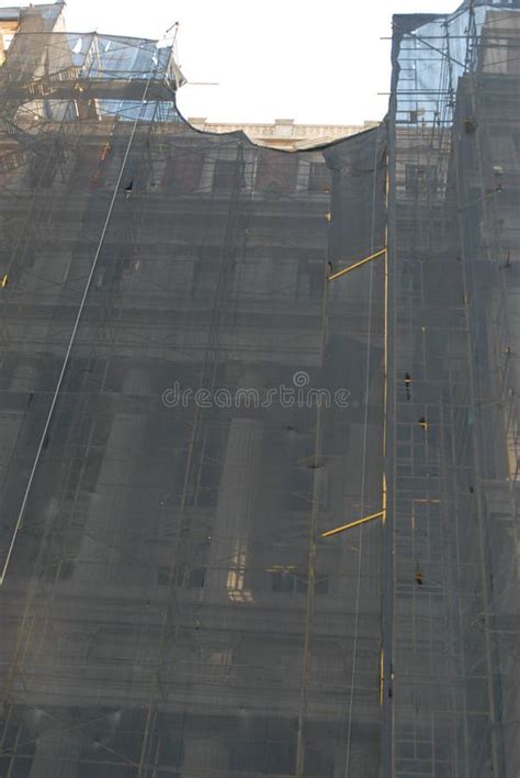 scaffolding and netting covering the facade of a tall building being