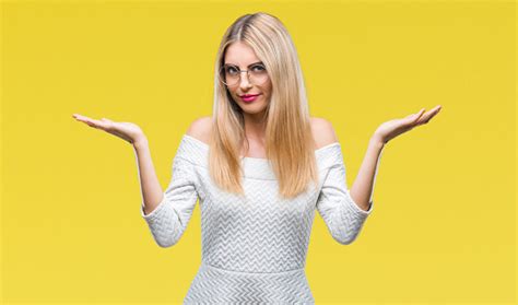 젊은 아름 다운 금발 여자는 팔과 손을 제기와 고립 된 배경 유 두와 혼동 표현 위에 안경을 착용 의심의 개념입니다 감정에 대한 스톡 사진 및 기타 이미지 Istock