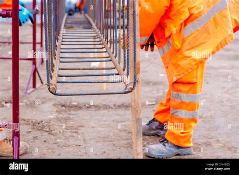Builders Hands Fixing Steel Reinforcement Bars At Construction Site