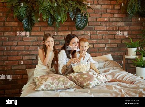 Maman S Assoit Sur Le Lit Avec Son Fils Et Sa Fille Et Regarde Un Film Une Femme Un Gar On Et