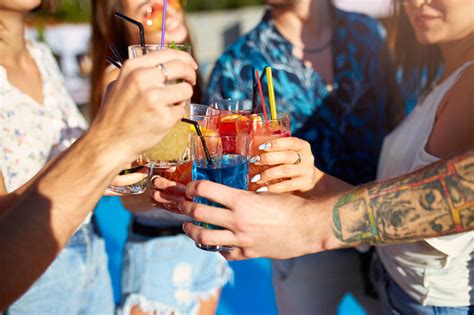 수영장 옆 여름 파티에서 즐거운 시간을 보내는 친구들의 가까이에서 볼 수 있으며 호텔 수영장 야외 근처에서 신선한 여름 칵테일과 함께 안경을 깜박입니다 휴가에 고급 빌라에서