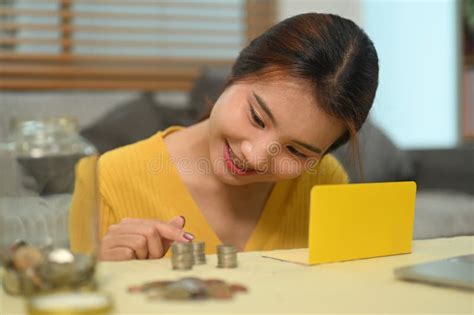 Young Woman Organizing Or Budgeting Her Savings At A Table In A Living