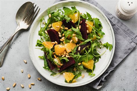 오래된 콘크리트 테이블 배경에 세라믹 접시에 비트 오렌지 소나무 너트 올리브 오일 페타 치즈와 아루굴라 샐러드 맨 위 보기 가을에 대한 스톡 사진 및 기타 이미지 Istock