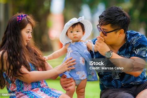 젊은 사랑 하 고 행복 한 아시아 한국 부모 부부 달콤한 딸 아가 건강 한 아름 다운 부모와 아동의 개념에서 녹색 도시 공원 잔디에 앉아 함께 즐기 가족에 대한 스톡 사진