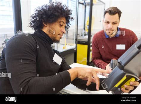 Two Engineers Engaged In Programming A Robotic System With A Gripper Arm Focusing On Industrial