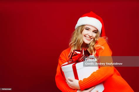 빨간 배경에 선물을 가진 산타클로스 모자를 쓴 아름다운 젊은 여성 12월에 대한 스톡 사진 및 기타 이미지 12월 개념 겨울 Istock