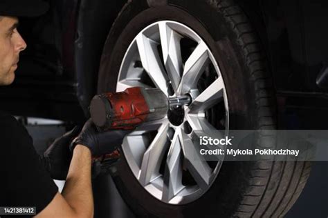 수리 주유소에서 리프트 된 자동차의 자동차 휠을 교체하는 자동차 정비사 작업장에서 바퀴의 조립 또는 해체 수리 및 서비스중인 자동차의 유지 보수 35 39세에 대한 스톡