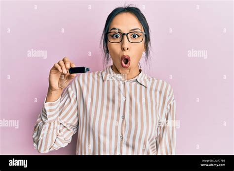 Young Hispanic Girl Holding Removable Memory Usb Scared And Amazed With