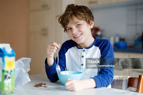 아침 이나 점심 시리얼을 먹는 행복 한 작은 금발 아이 소년 어린이를위한 건강한 식사 우유와 뮤즐리와 함께 아침 식사를 하는 다채로운 잠옷의 아이 아침식사 시리얼에 대한