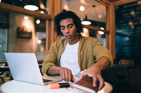 시험을 준비하고 카페테리아에서 기술을 통해 숙제를하는 펜시브 곱슬 남학생 랩톱 컴퓨터에서 원격으로 작업하는 사려 깊은 남자 프리랜서 검색 및 데이터 검색 25 29세에 대한