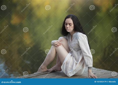 A Young Woman Sits On The Bridge By The Water Nymph Girl At The Lake
