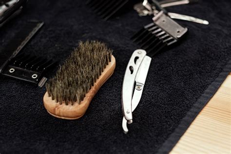 이발소에서 일하는 이발사 도구 내추럴베이스 브러시 빗 위험한 면도기 노즐이있는 면도 기계는 모두 고객의 이발을 위해 검은 테리 수건에 있습니다 헤어와 턱수염 관리와 미용 0