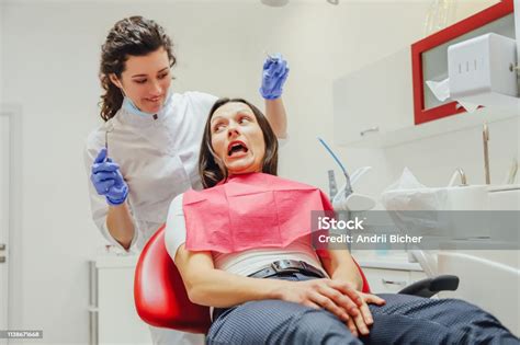 한 청 녀는 치과 기구가 활짝 열린 눈을 바라보는 것을 두려워 하는 것에 충격을 받았다 치과 의사와 치과 치료에 대 한 두려움의 개념 2명에 대한 스톡 사진 및 기타 이미지