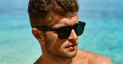 여름에 남자 스킨 케어 선글라스를 끼고 섹시한 몸매를 가진 잘생긴 남성이 일광욕을 하기 전에 자외선 차단 자외선 차단제 로션을