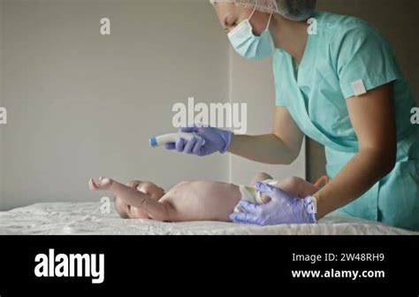 Pediatrician Measures The Temperature Of The Newborn With A Non Contact