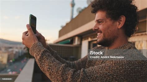 행복한 남자는 새벽에 발코니에 서서 스마트폰으로 아름다운 경치를 사진 비디오로 찍는다 30 34세에 대한 스톡 사진 및 기타 이미지 30 34세 그루터기 얼굴부위 털