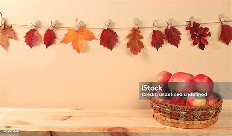 단풍 나무 잎과 사과 바구니가있는 빈 부엌 나무 음식 디스플레이 테이블 최소한의 가을 개념 스크린 배너가있는 창조적 인 가을 구성 행복한 추수 감사절과 인사말 카드 선택적