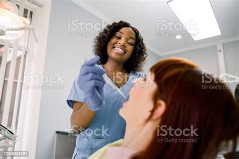 의학 치과 및 의료 개념 치과 용 거울과 도구를 가진 미소 짓는 전문 아프리카 여성 치과 의사의 하단 보기 현대 치과 진료소에서 어린 소녀 환자의 치아를 확인 25 29세에