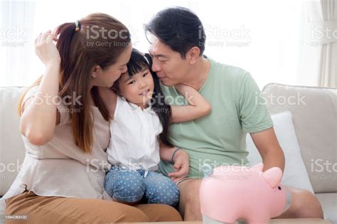 행복한 아시아 가족 아버지와 어머니는 집 거실의 소파에 앉아 뺨에 키스하는 딸 아빠와 엄마 아이는 소파 라이프스타일 관계 개념에